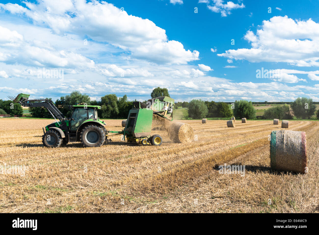 tractor throwing out hay roll Stock Photo - Alamy