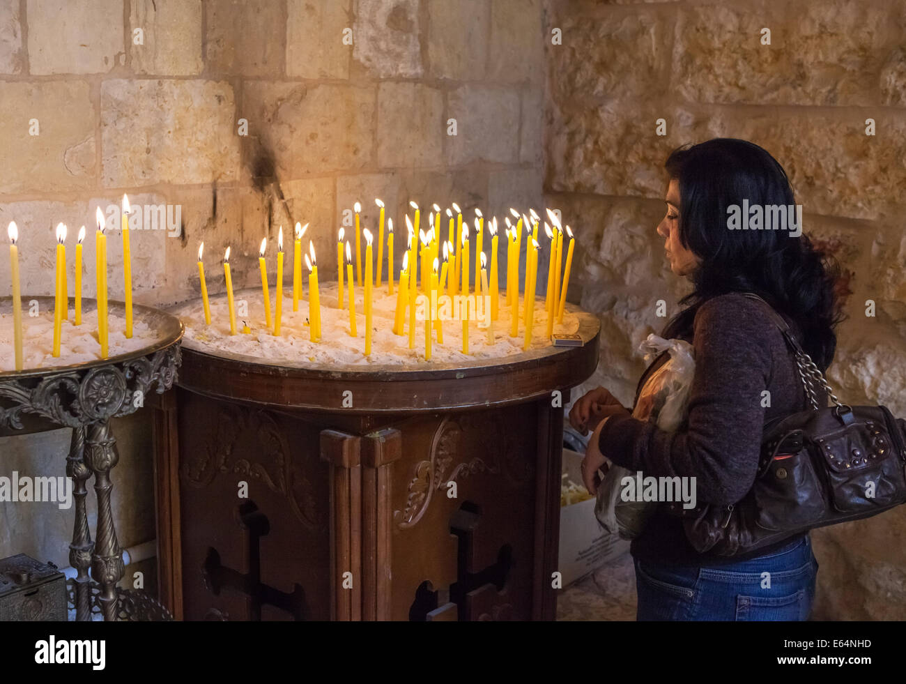 A Jordanian Christian woman, praying before lit candles, at the old ...