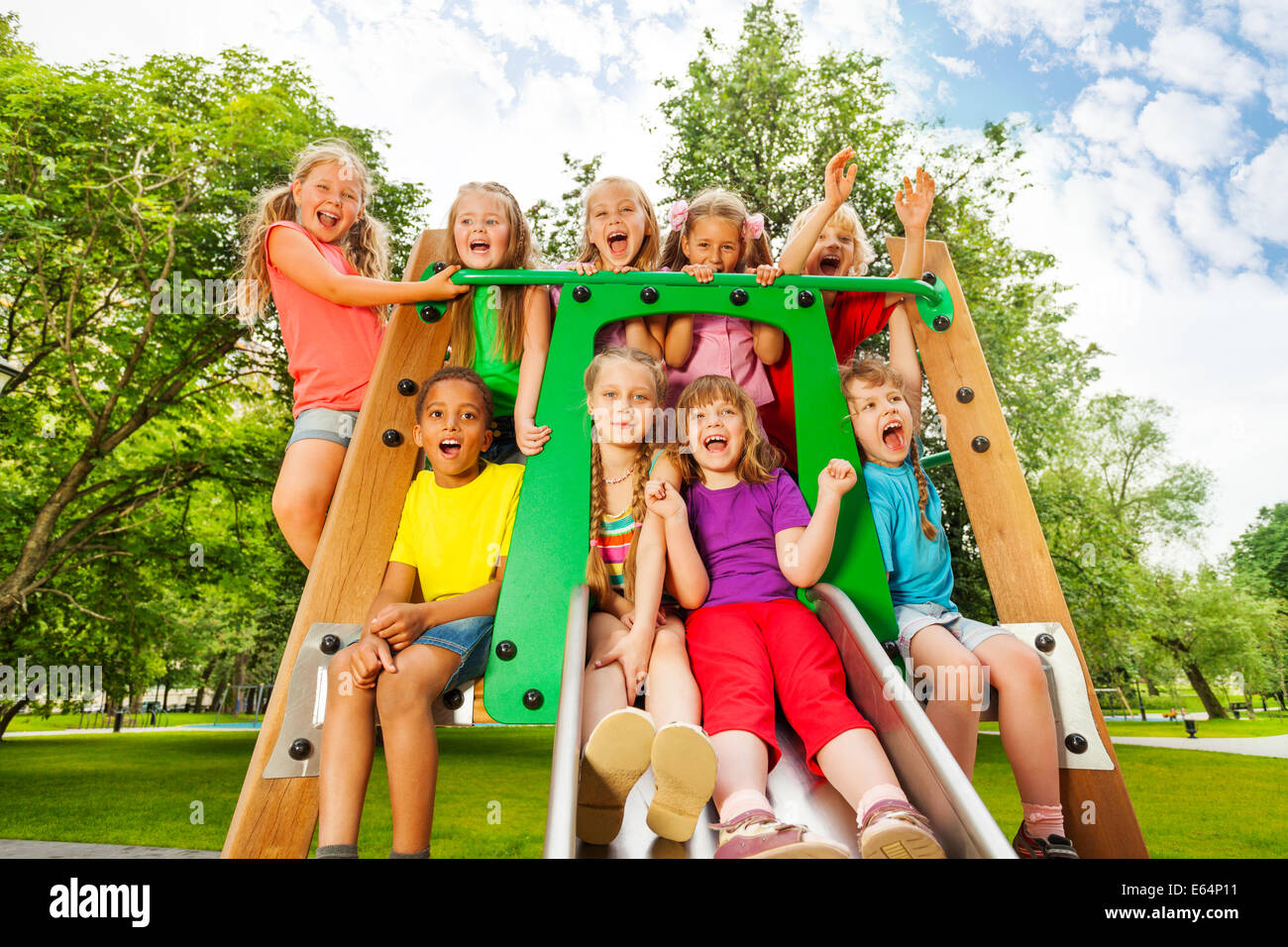 Funny children on playground chute with arms up Stock Photo - Alamy