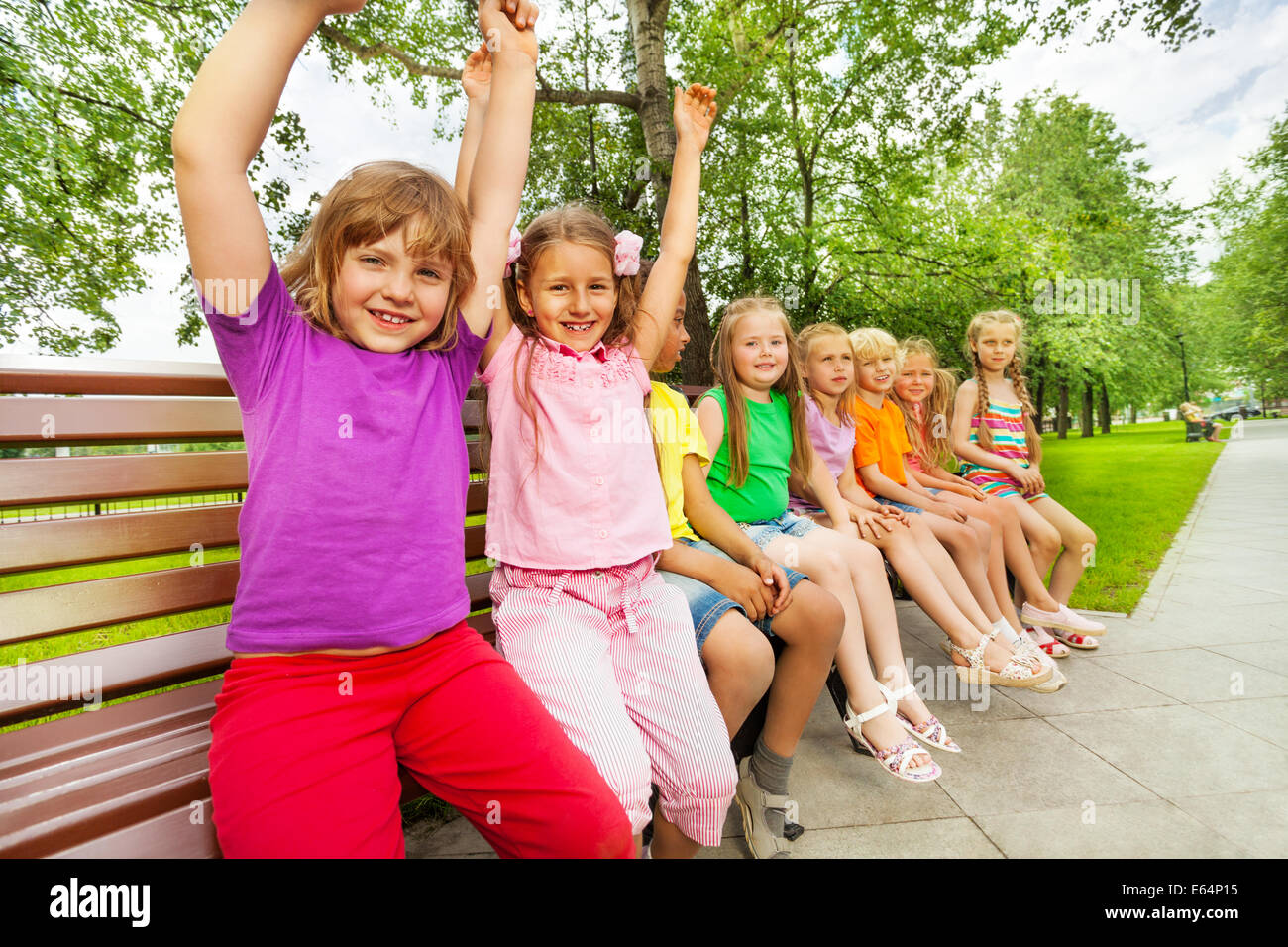 Smiling children sit in row on the bench Stock Photo - Alamy