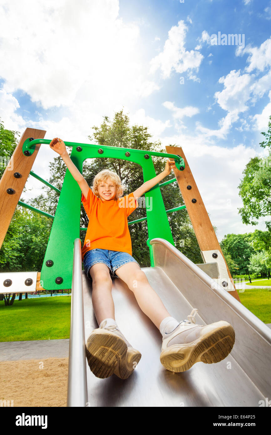 Boy sliding on metallic chute with hands up Stock Photo - Alamy