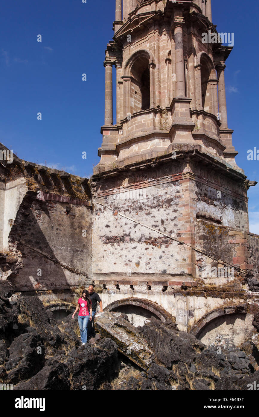 A couple walks on the lava rock near the temple ruins of the Paricutin ...