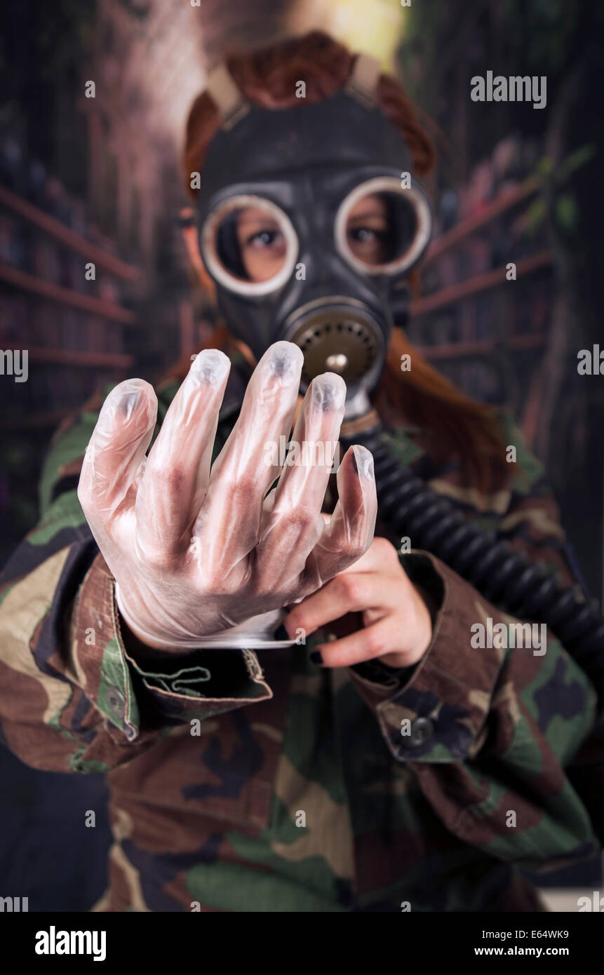Young girl wearing military uniform and gas mask over dark background ...
