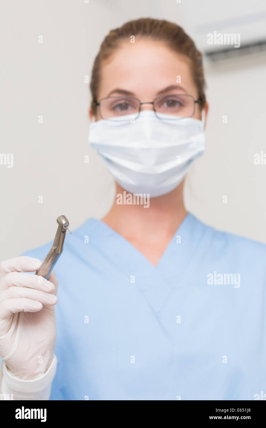 Dentist in blue scrubs holding drill looking at camera Stock Photo - Alamy
