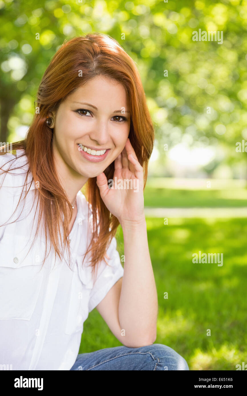 Pretty redhead smiling at camera in the park Stock Photo - Alamy
