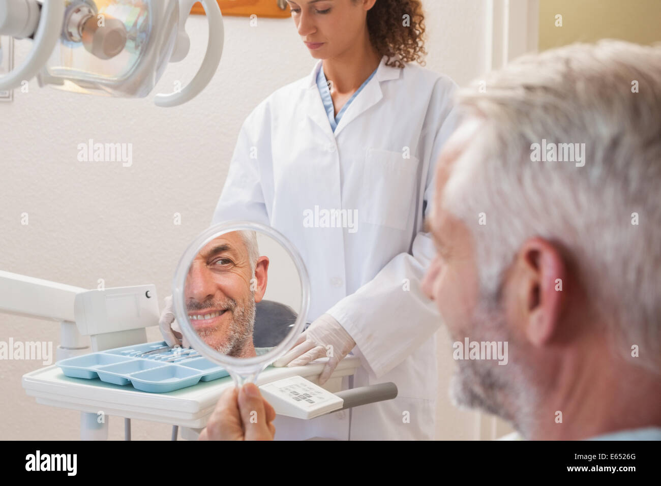 Patient admiring new smile in the mirror Stock Photo - Alamy