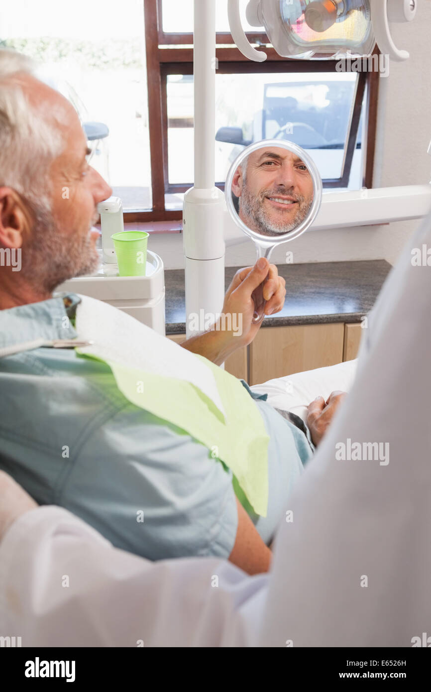 Patient admiring new smile in the mirror Stock Photo - Alamy