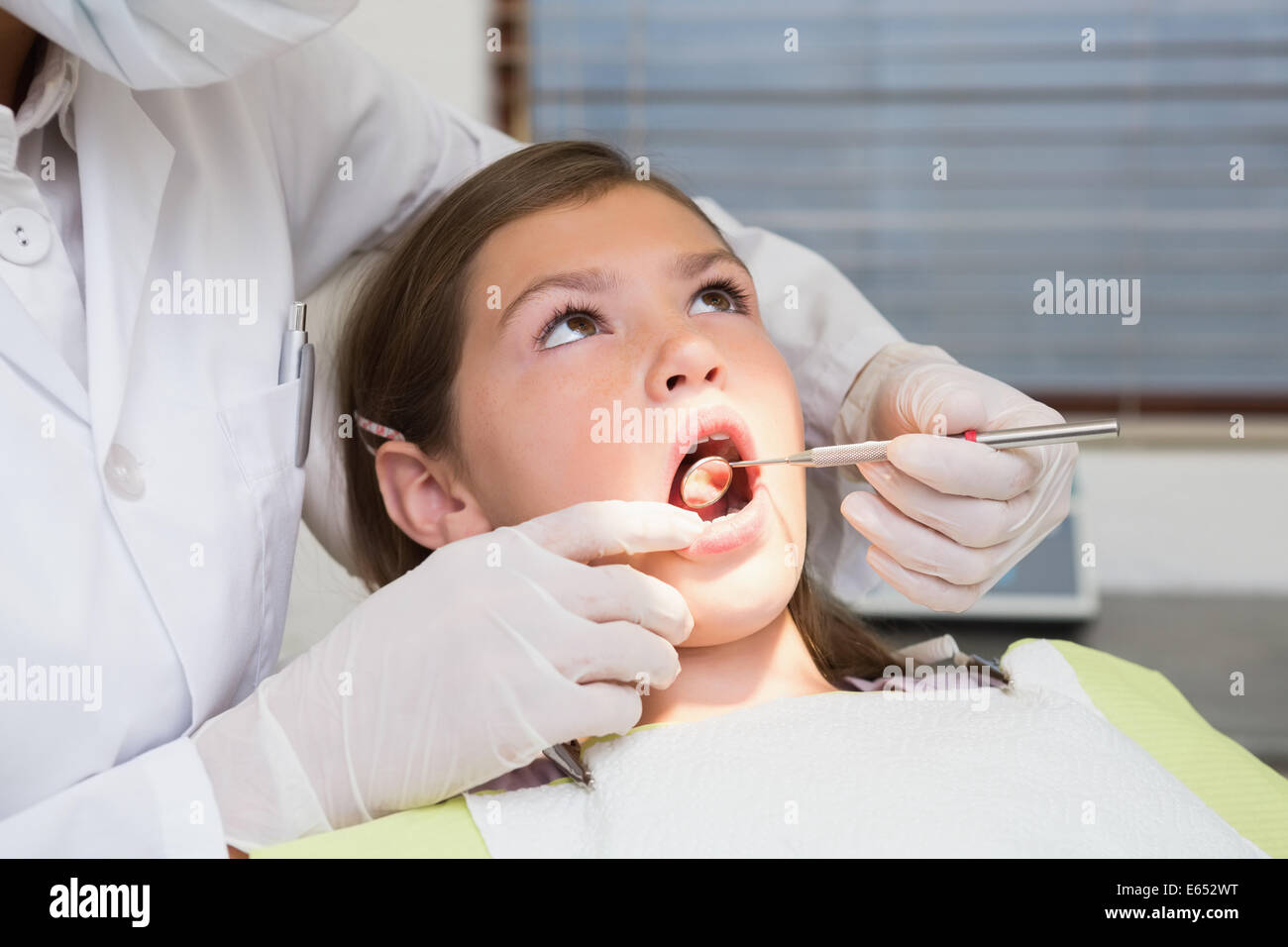 Pediatric dentist examining a little girls teeth in the dentists chair ...