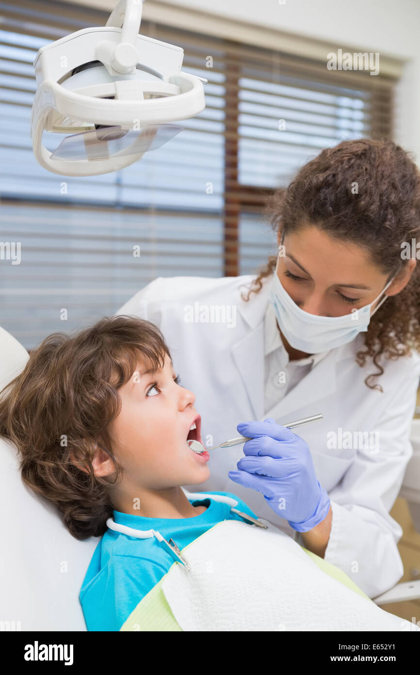 Pediatric dentist examining a little boys teeth in the dentists chair ...