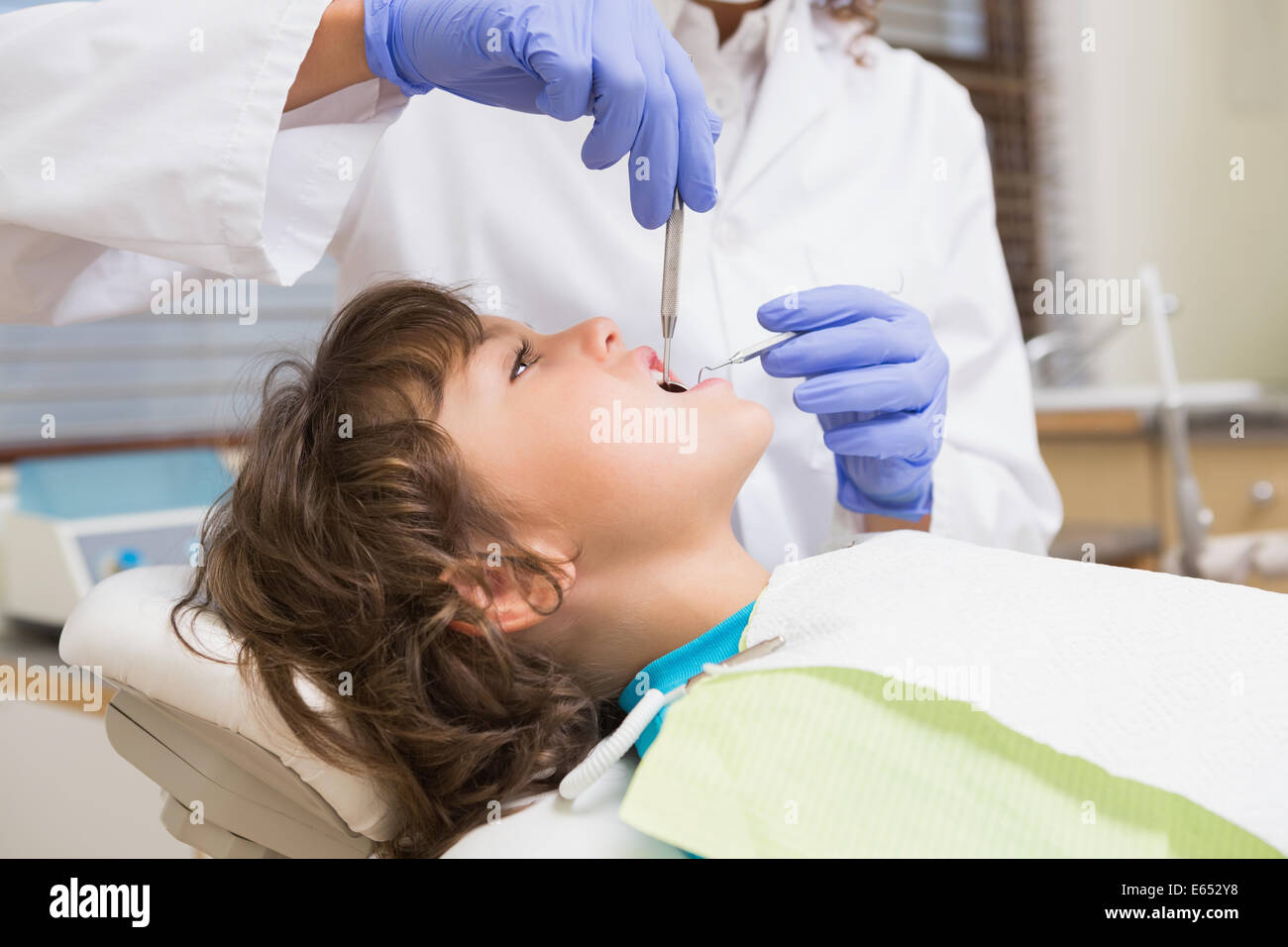 Pediatric dentist examining a little boys teeth in the dentists chair ...