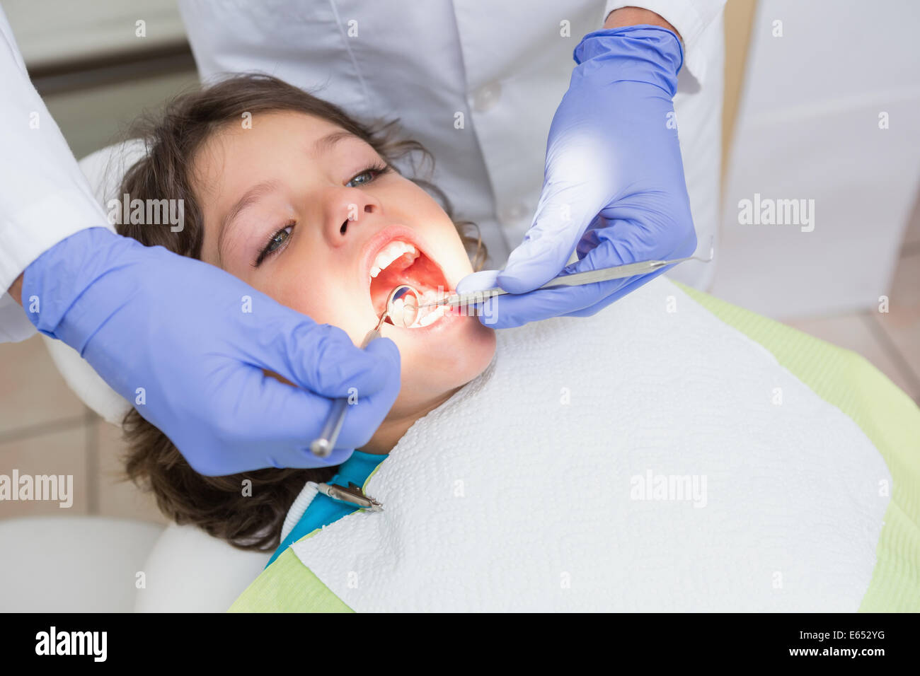 Pediatric dentist examining a little boys teeth in the dentists chair ...