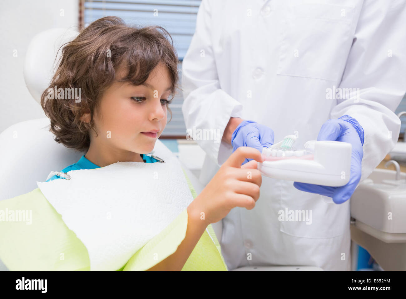 Pediatric dentist showing little boy teeth model Stock Photo - Alamy