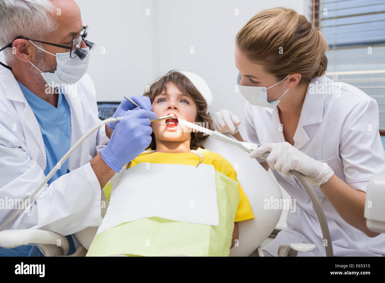 Pediatric dentist examining a little boys teeth in the dentists chair ...