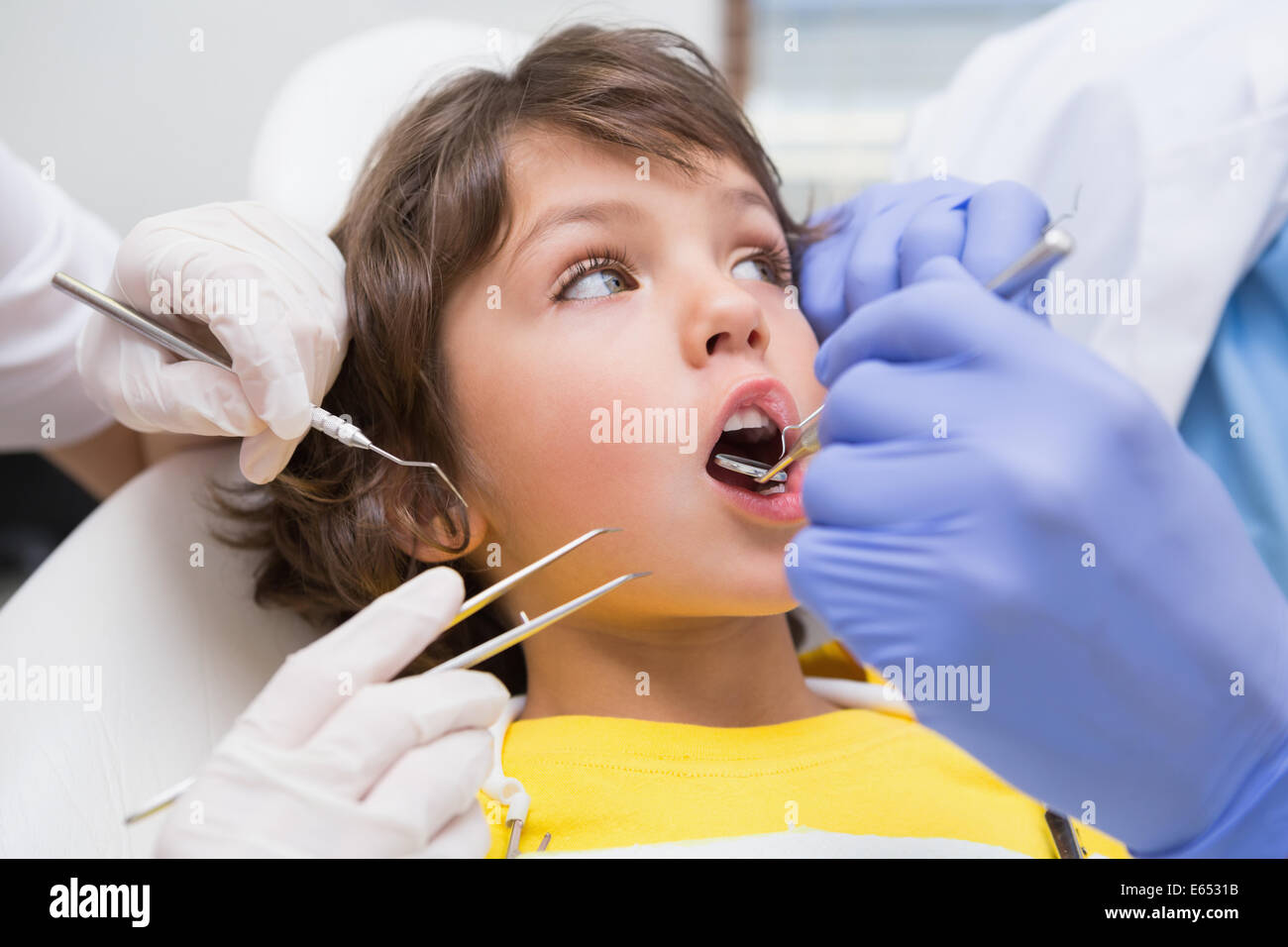 Pediatric dentist examining a little boys teeth with his assistant ...