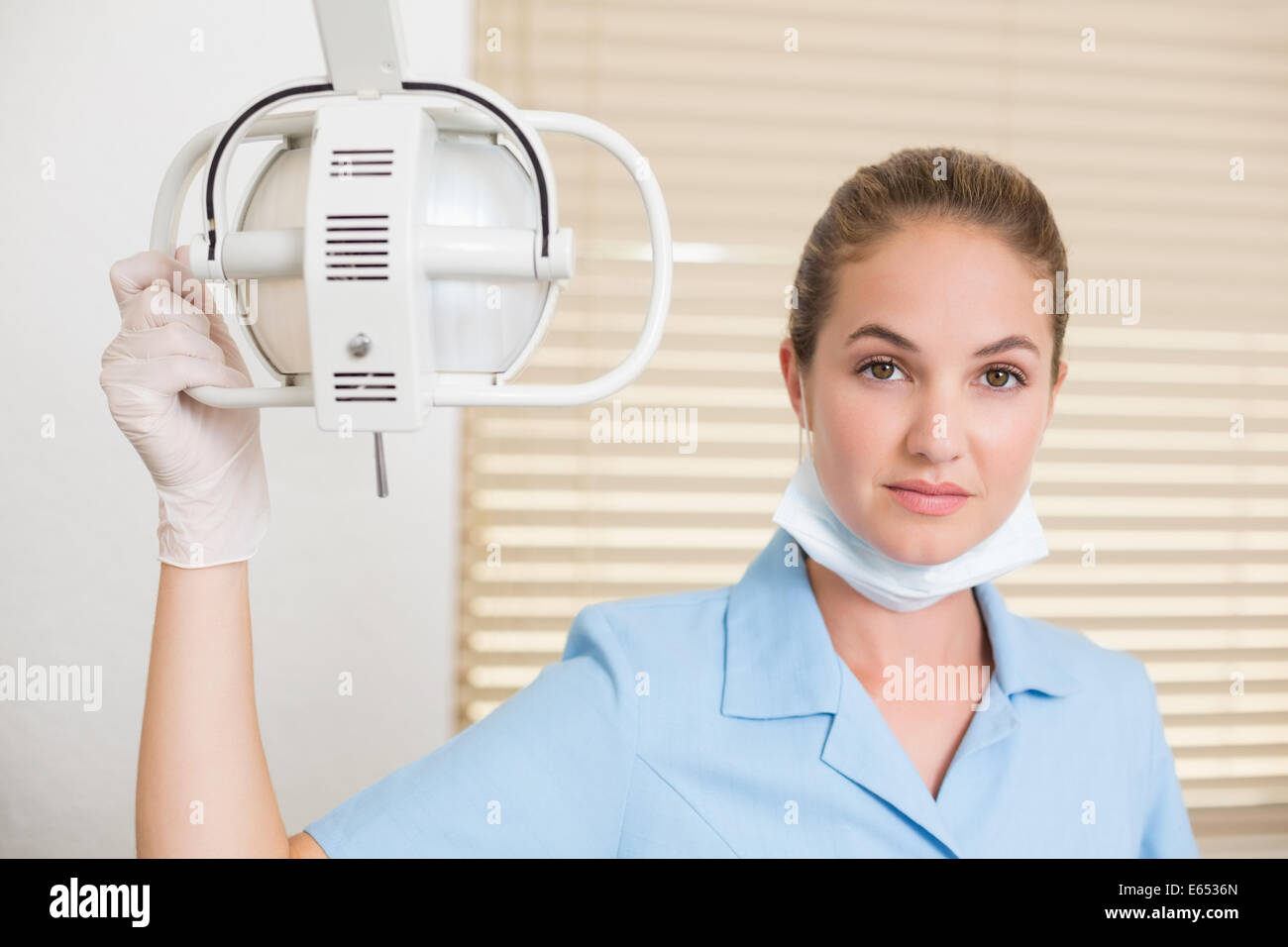 Dental assistant smiling at camera beside light Stock Photo - Alamy