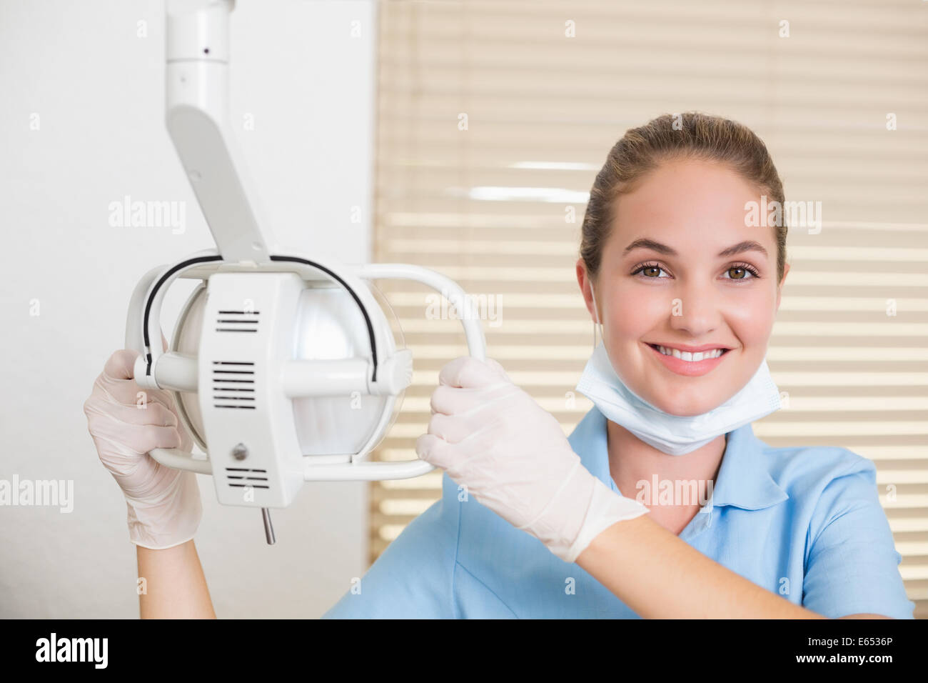 Dental assistant smiling at camera beside light Stock Photo - Alamy