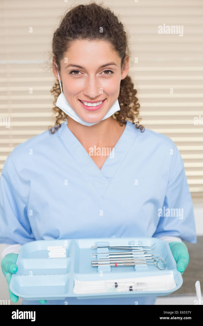 Dentist in blue scrubs holding tray of tools Stock Photo - Alamy