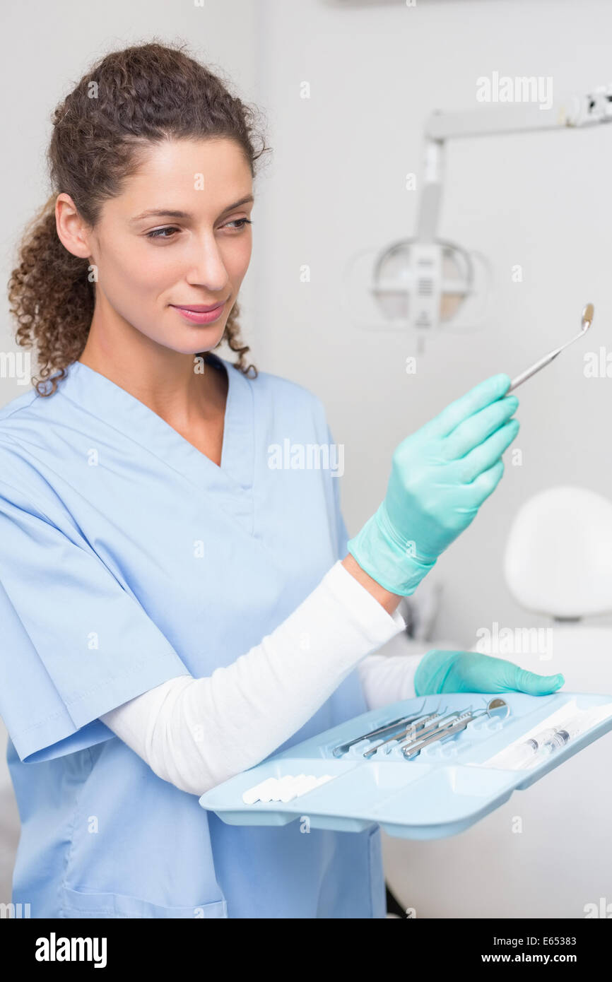 Dentist in blue scrubs holding tray of tools Stock Photo - Alamy