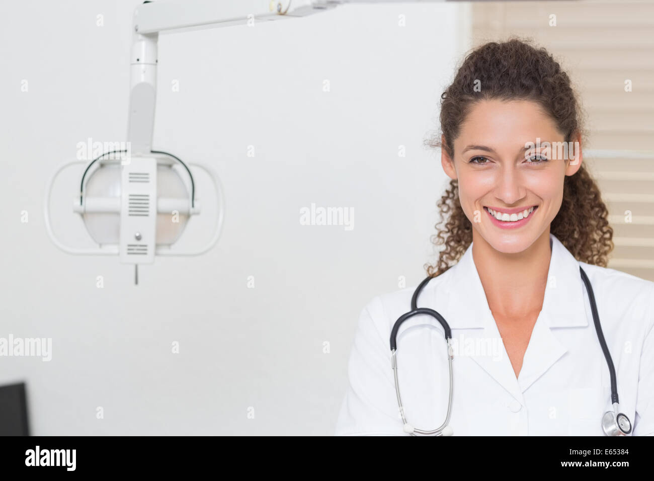 Dental assistant smiling at camera beside light Stock Photo - Alamy