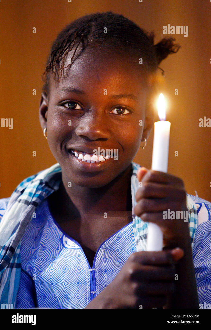 Girl (11 years) holding candle in a catholic church in Kaolack, Senegal ...