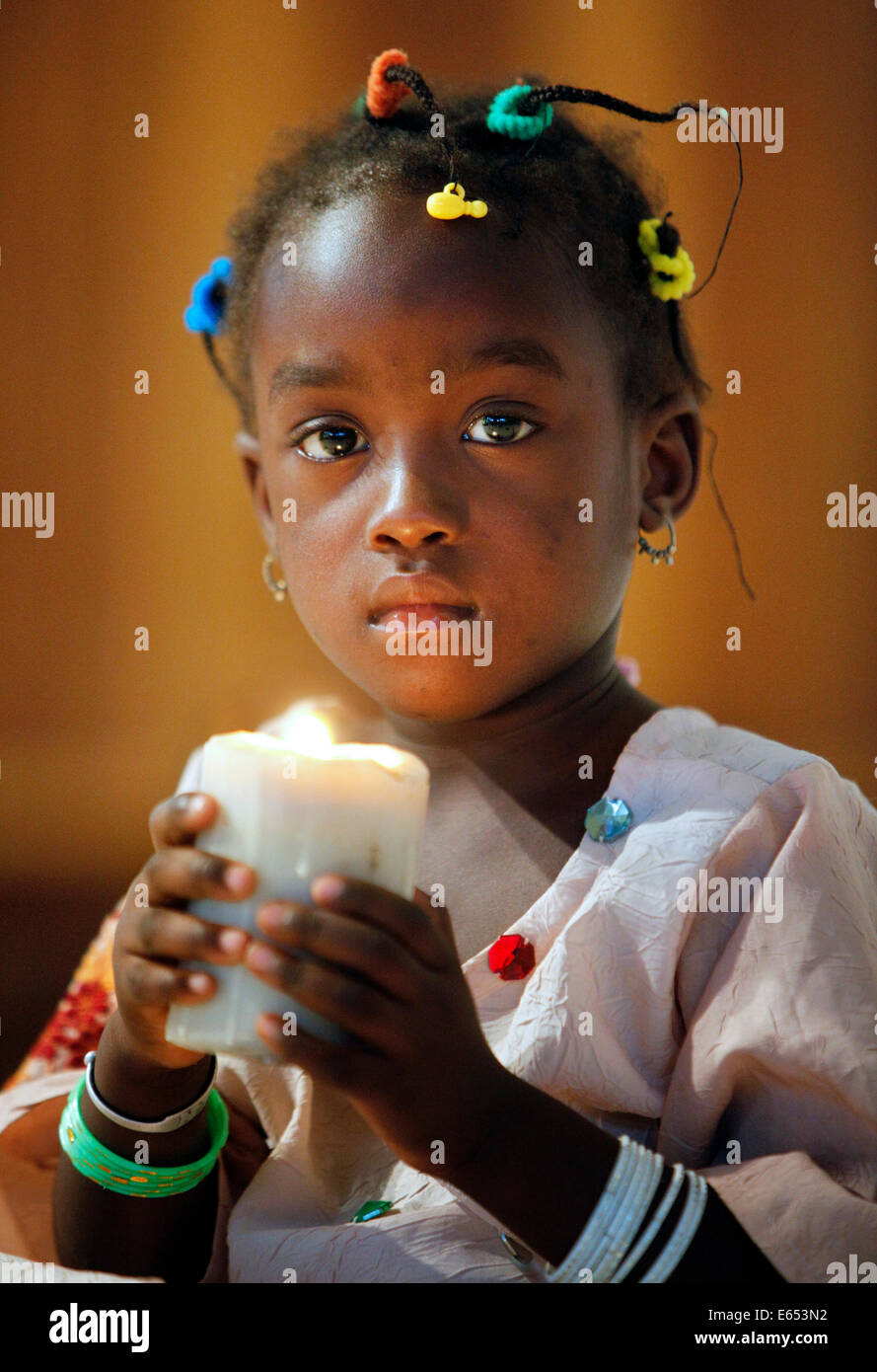 Girl (3 years) holding candle in a catholic church in Kaolack, Senegal ...