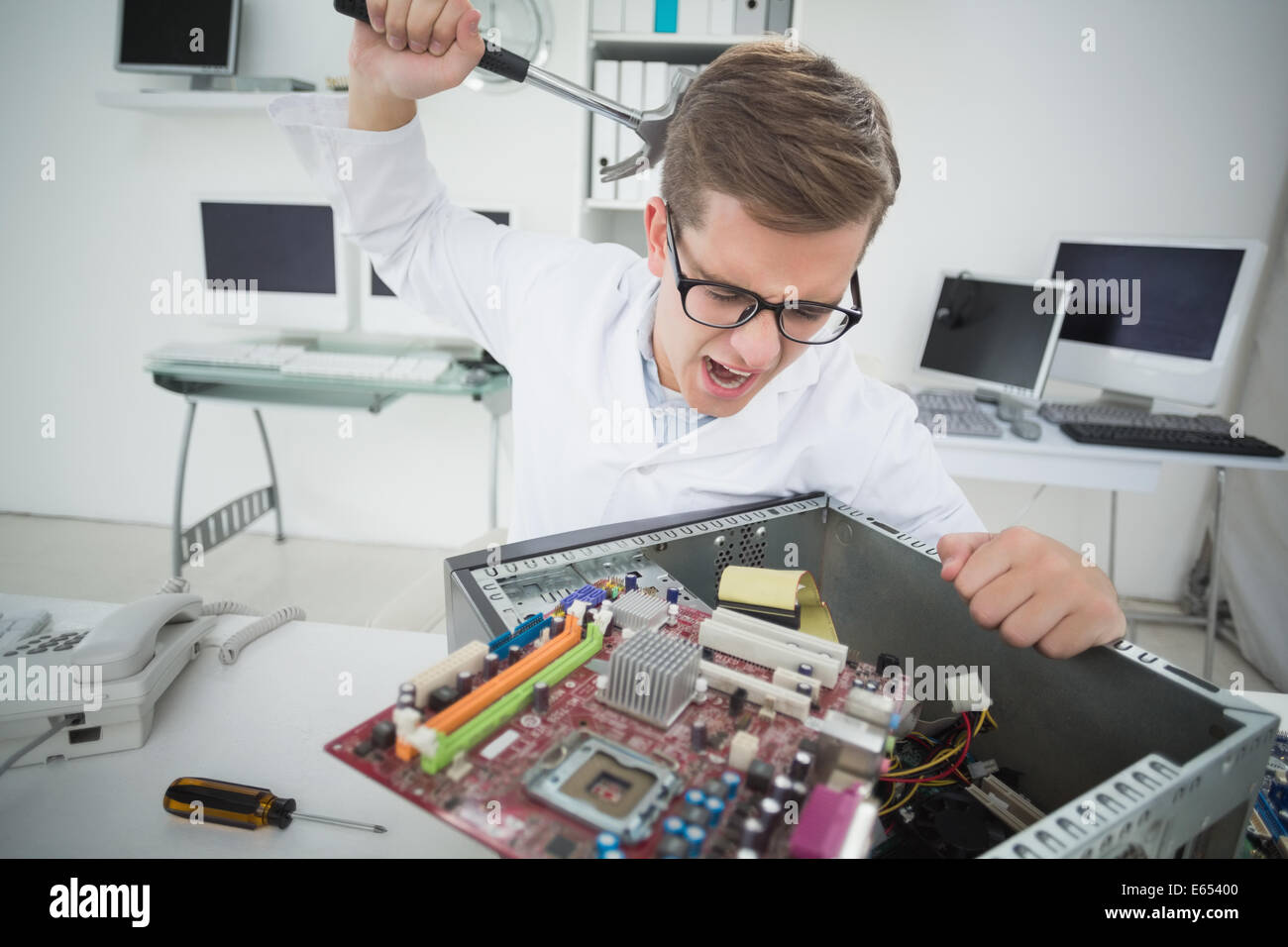Computer engineer holding hammer over broken console Stock Photo - Alamy
