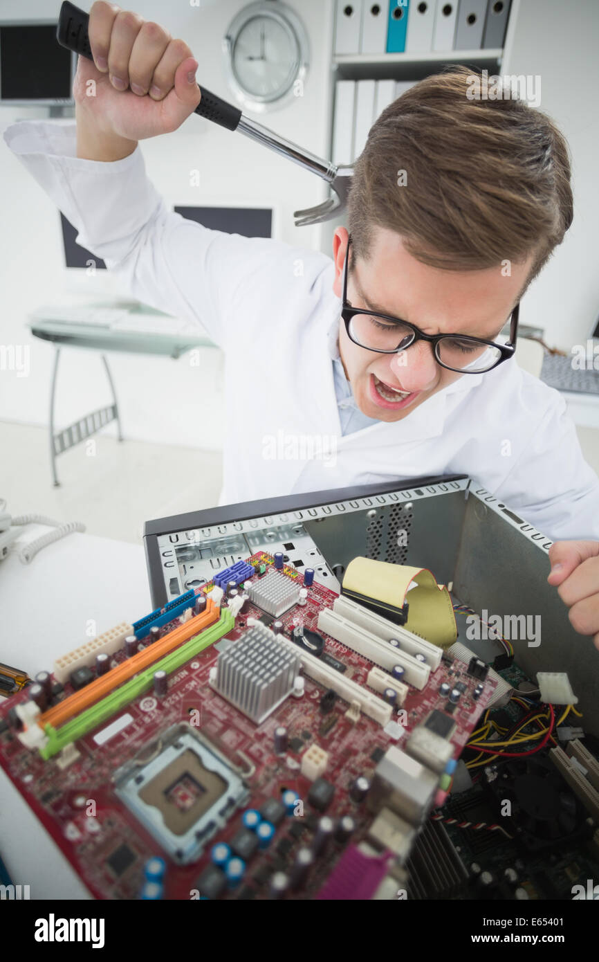 Computer engineer holding hammer over broken console Stock Photo - Alamy