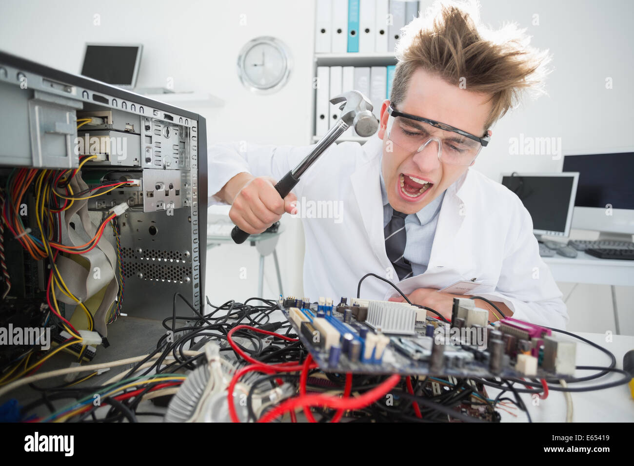 Angry computer engineer holding hammer over console Stock Photo - Alamy