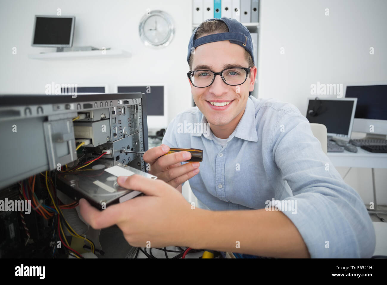 Smiling computer engineer working on broken console with screwdriver ...