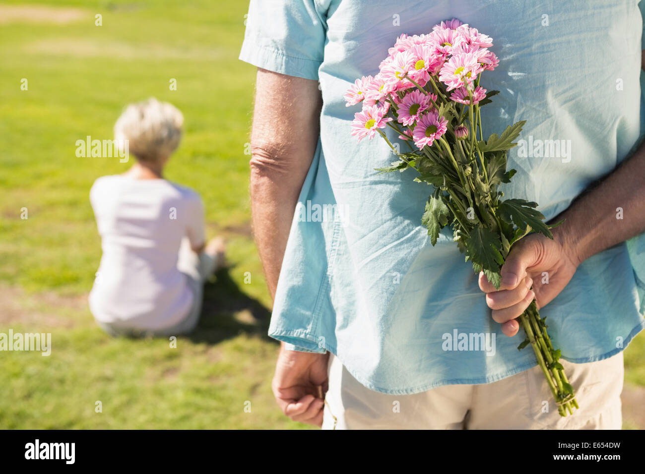 Senior man hiding flowers behind his back Stock Photo - Alamy