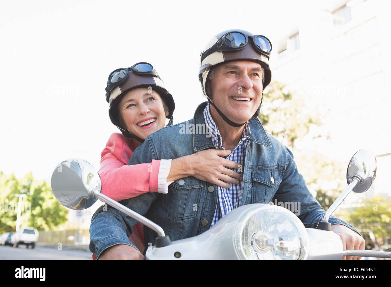 Happy senior couple riding a moped Stock Photo - Alamy