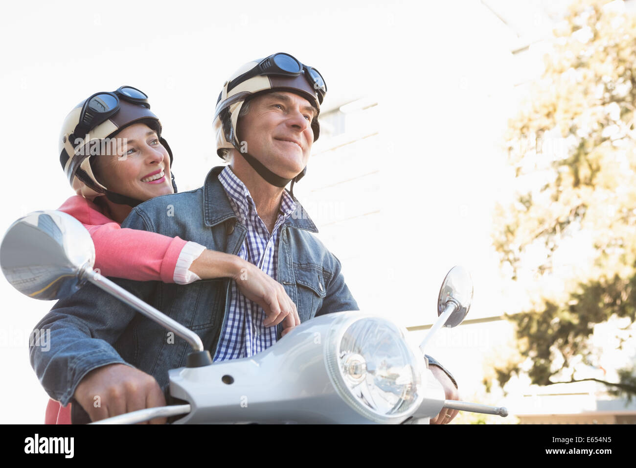 Happy senior couple riding a moped Stock Photo - Alamy