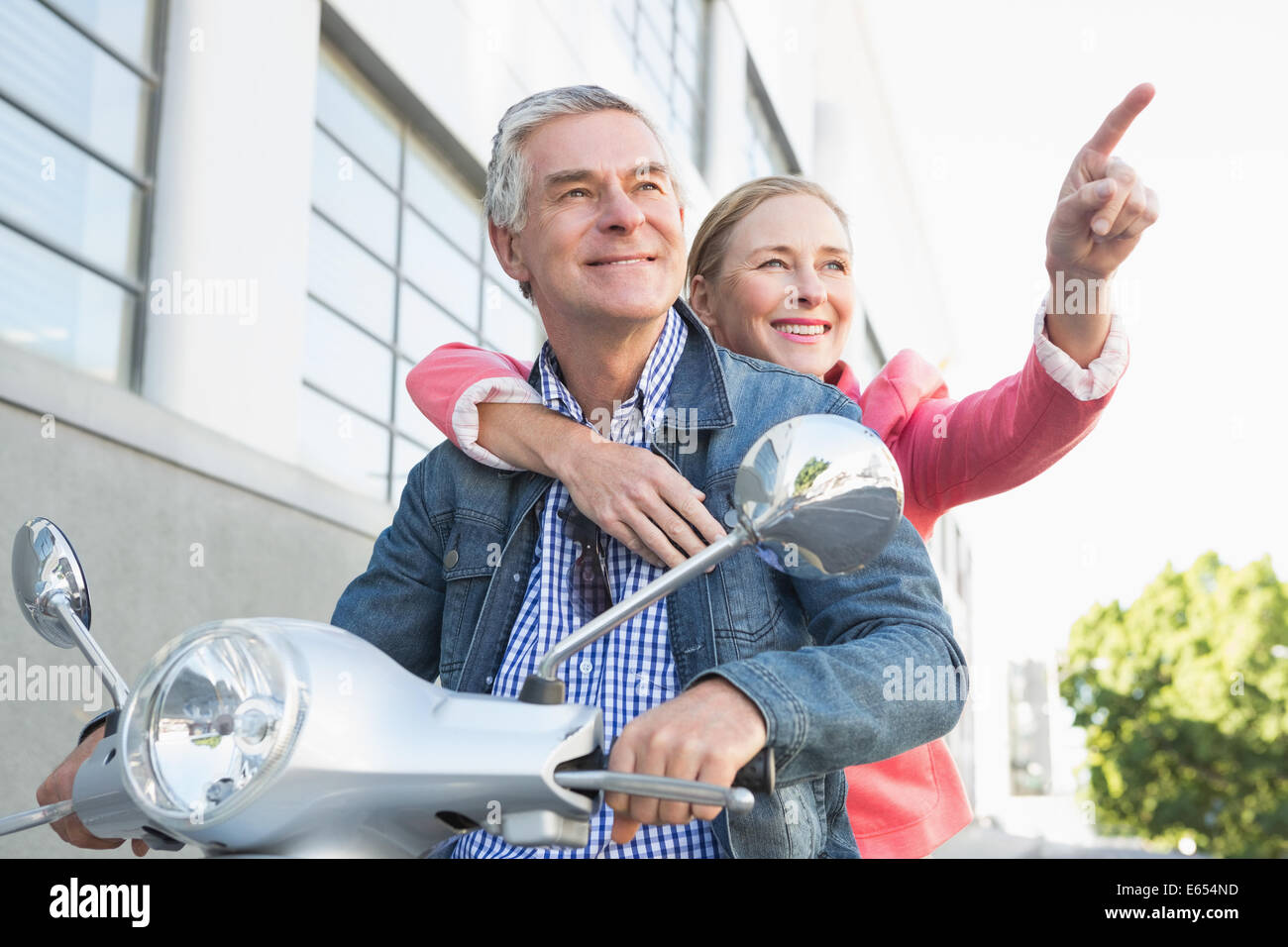 Happy senior couple riding a moped Stock Photo - Alamy