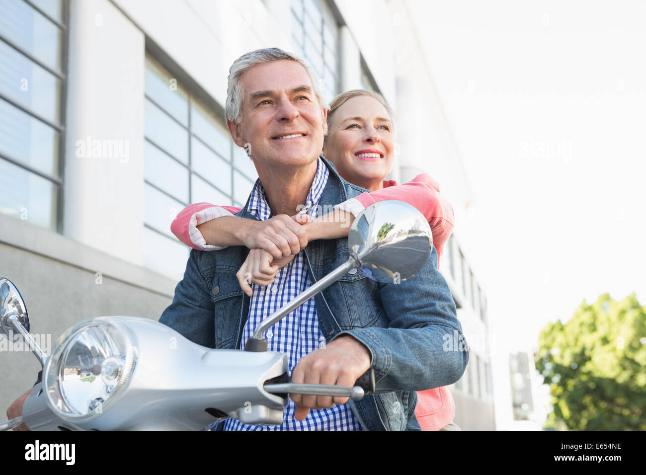 Happy senior couple riding a moped Stock Photo - Alamy