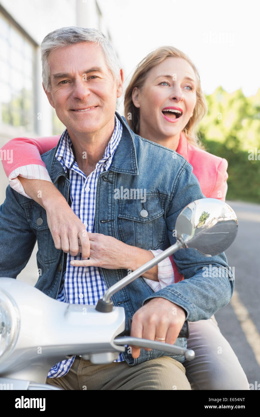 Happy senior couple riding a moped Stock Photo - Alamy