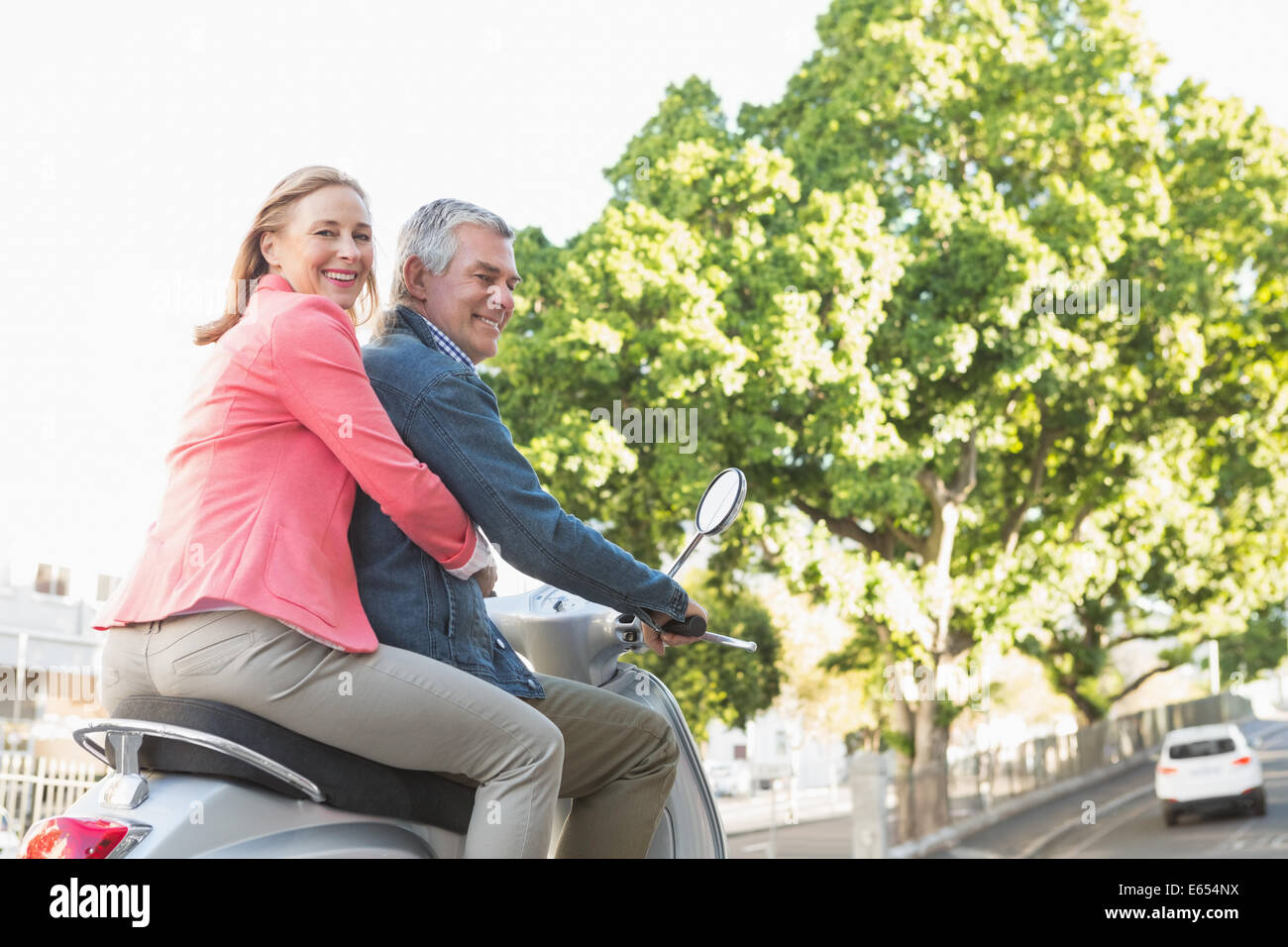 Happy senior couple riding a moped Stock Photo - Alamy