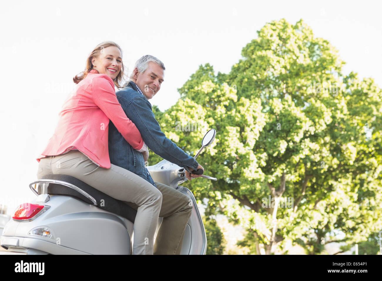 Happy senior couple riding a moped Stock Photo - Alamy