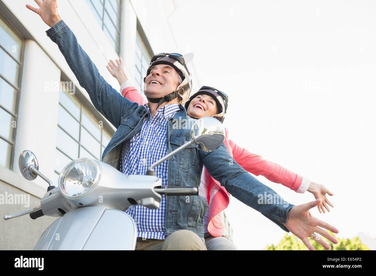 Happy senior couple riding a moped Stock Photo - Alamy