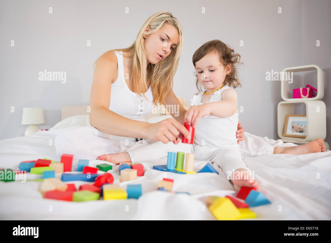 Mother and daughter playing with building blocks on bed Stock Photo - Alamy