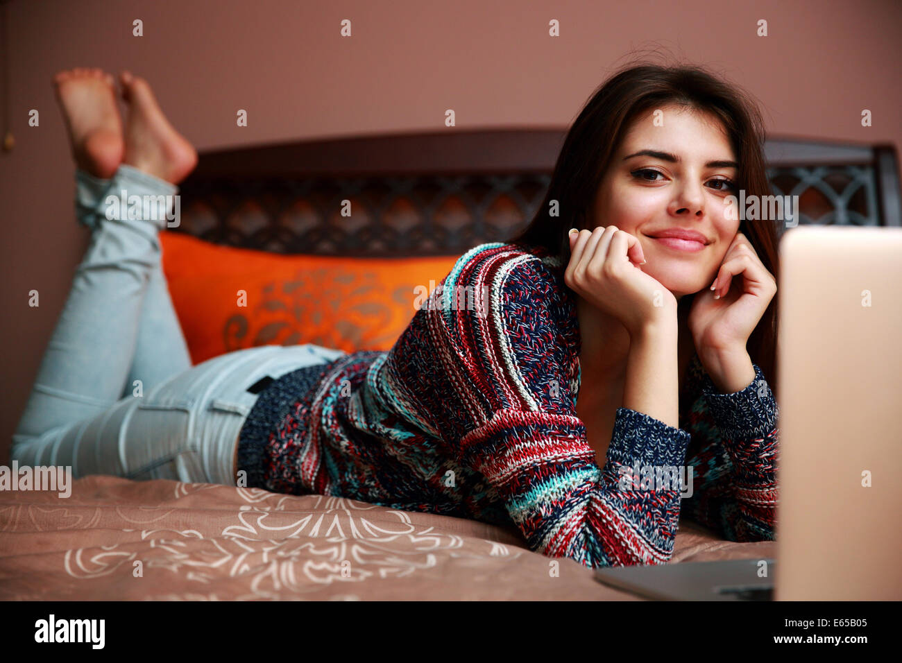 Smiling woman lying on the bed with laptop Stock Photo - Alamy