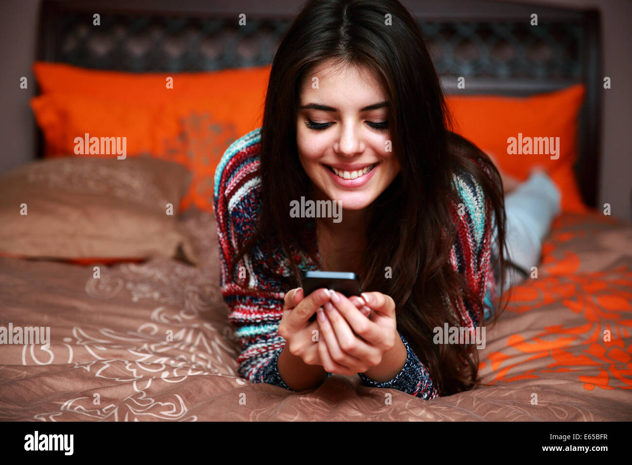 Happy beautiful woman lying on the bed with smartphone Stock Photo - Alamy