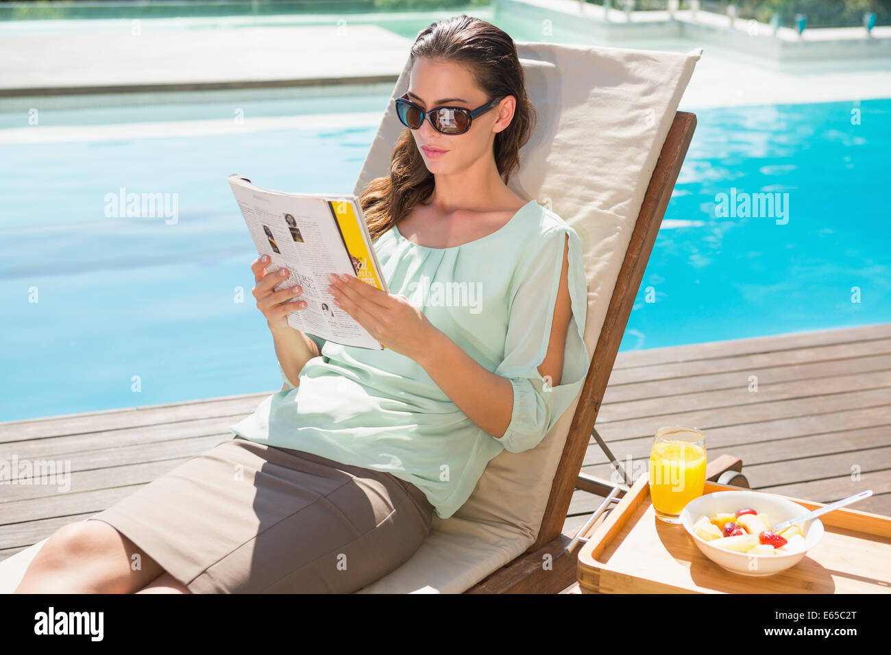 Woman reading book by pool hi-res stock photography and images - Alamy