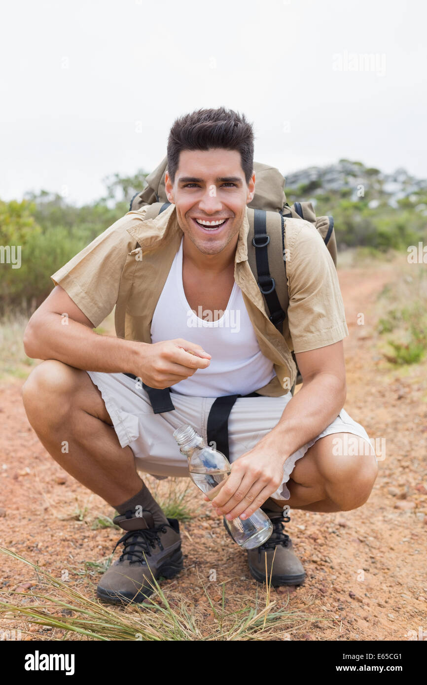 Cheerful hiking man crouching on mountain terrain Stock Photo - Alamy