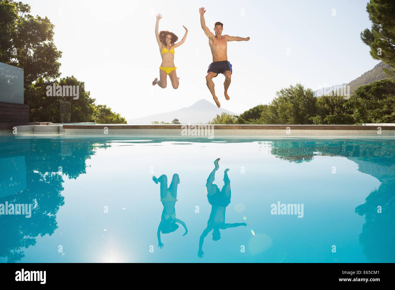 Cheerful couple jumping into swimming pool Stock Photo - Alamy