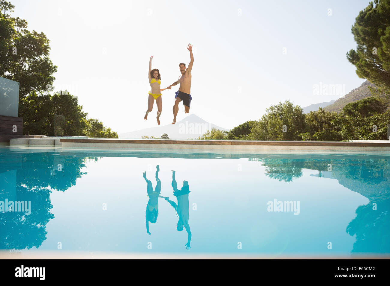 Cheerful couple jumping into swimming pool Stock Photo - Alamy
