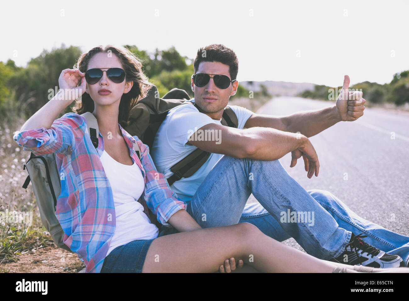 Couple hitchhiking on countryside road Stock Photo - Alamy