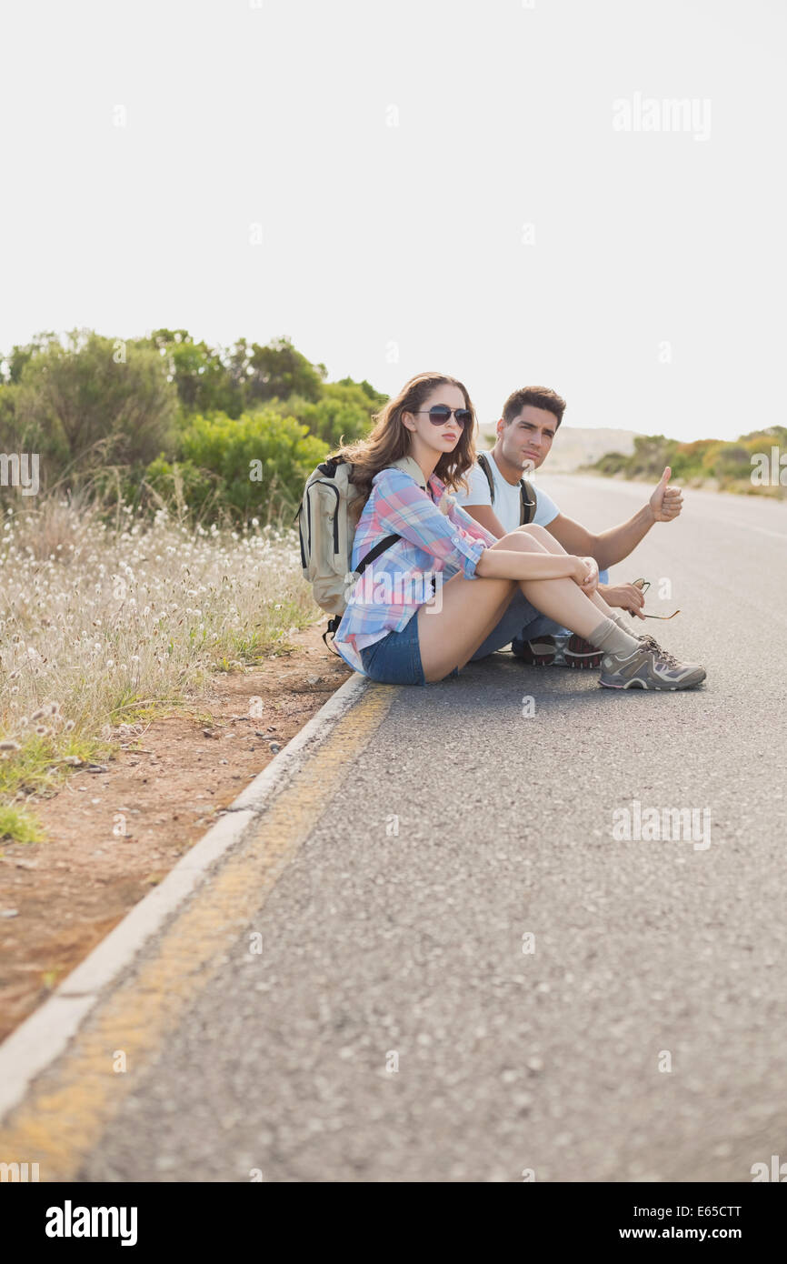 Couple hitchhiking on countryside road Stock Photo - Alamy