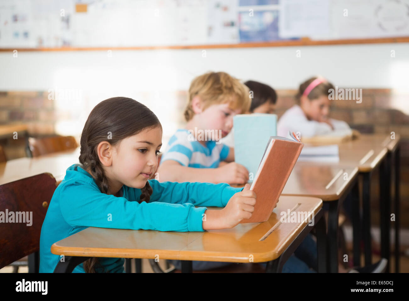 Pupils sitting in classroom reading books Stock Photo - Alamy