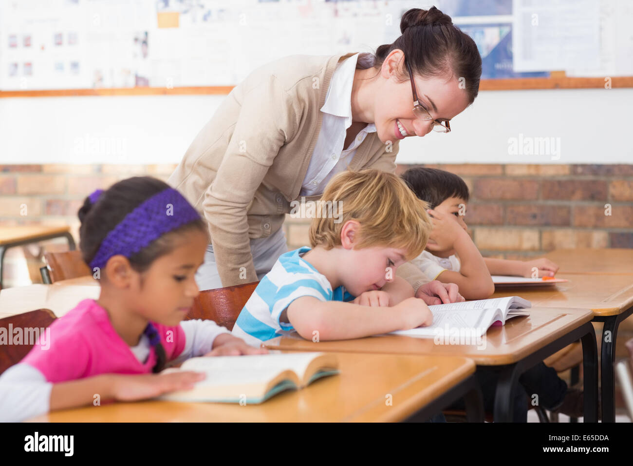 Pretty teacher helping pupil in classroom Stock Photo - Alamy