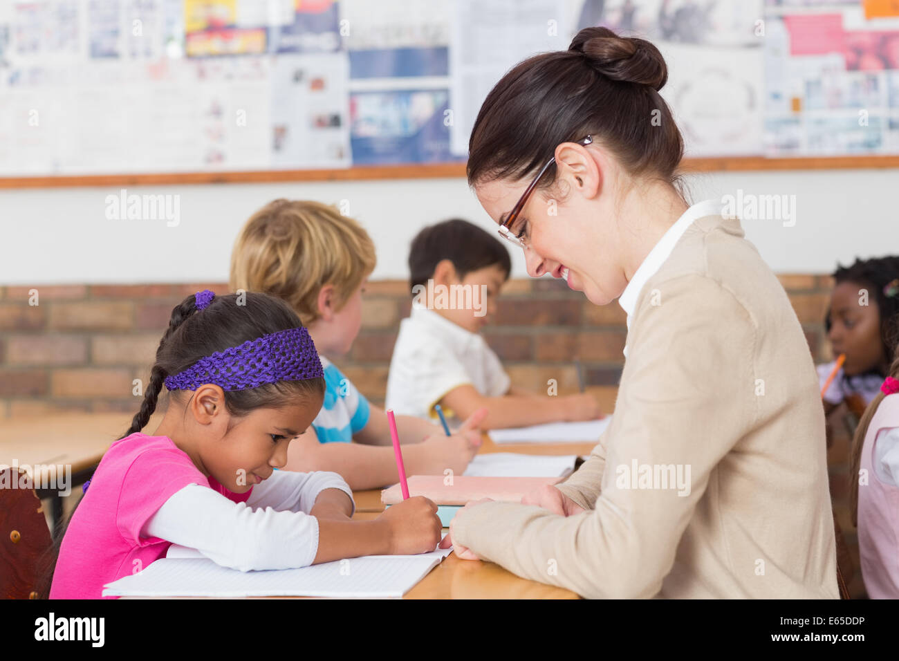 Pretty teacher helping pupil in classroom Stock Photo - Alamy